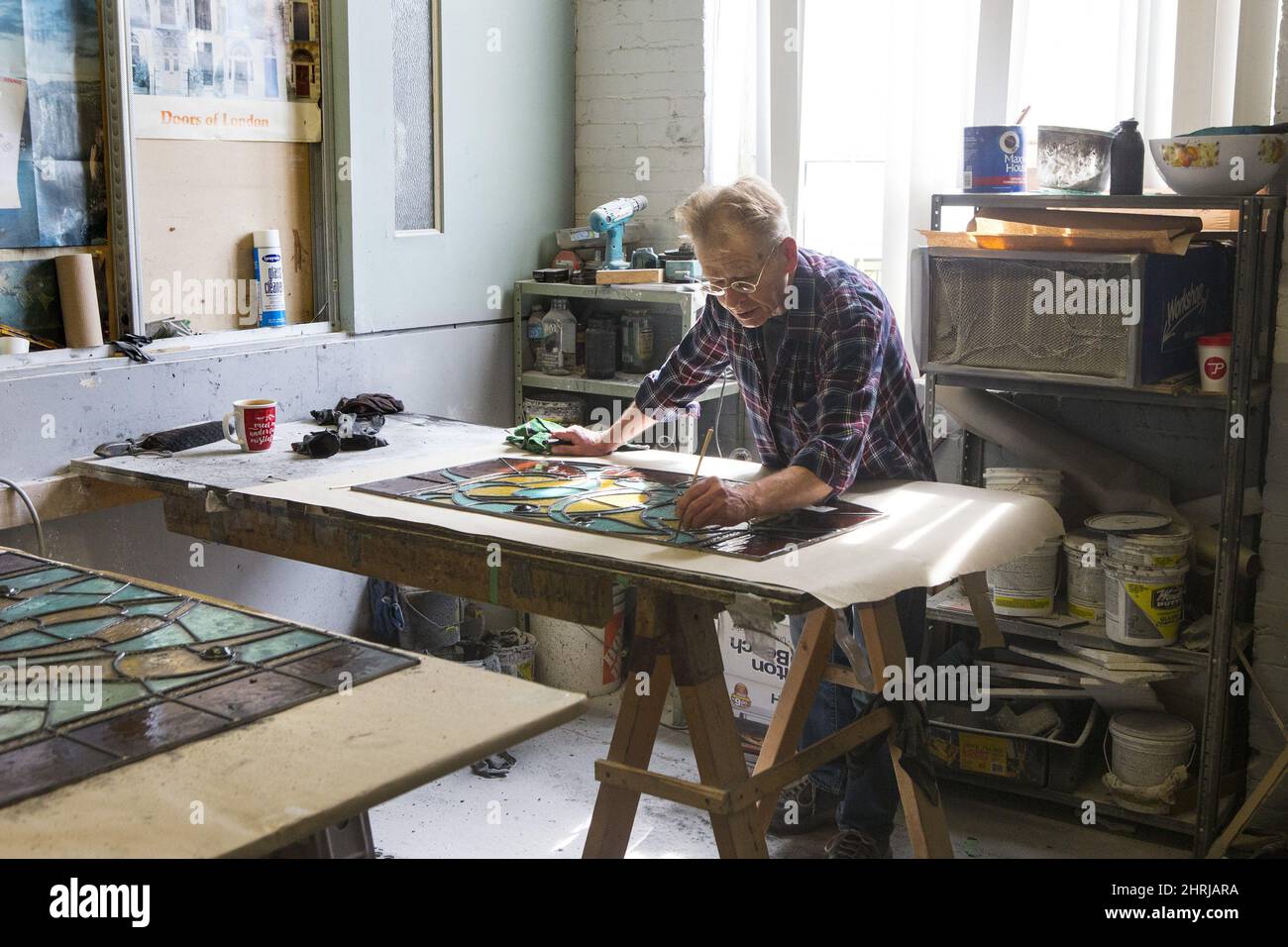 Lee Chantler works on cementing using a putty on a piece of glass ...