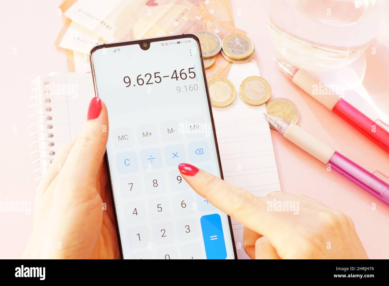 Girl calculating with a smartphone and coins in the background Stock ...