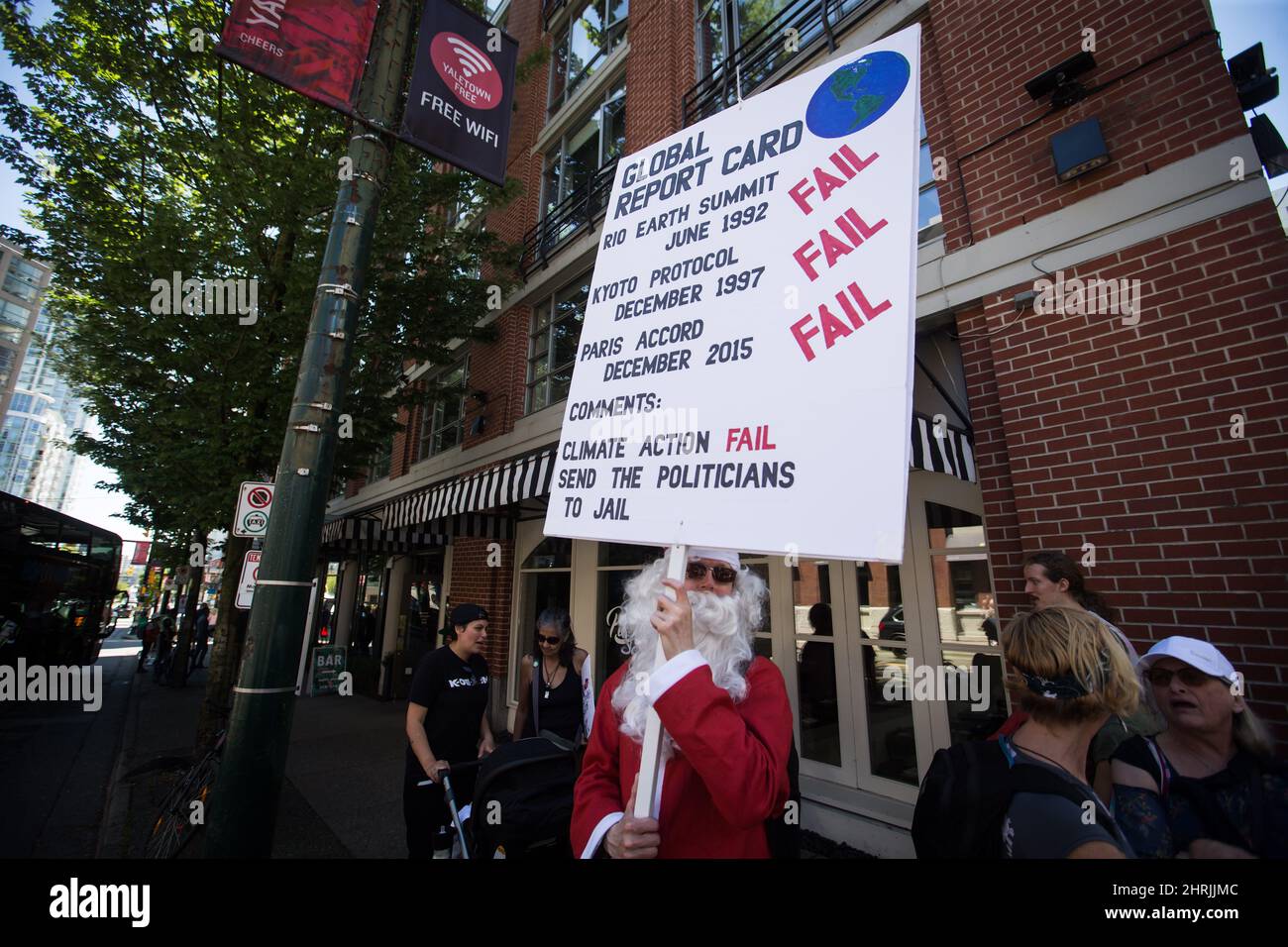 A protester dressed as Santa Claus holds a sign while standing outside ...