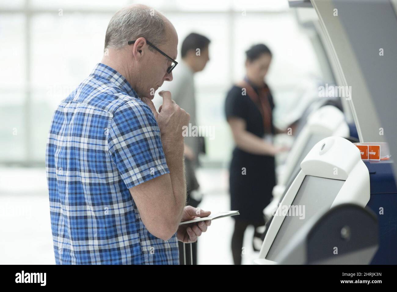 A passenger uses a self check-in booth at the departures terminal at ...