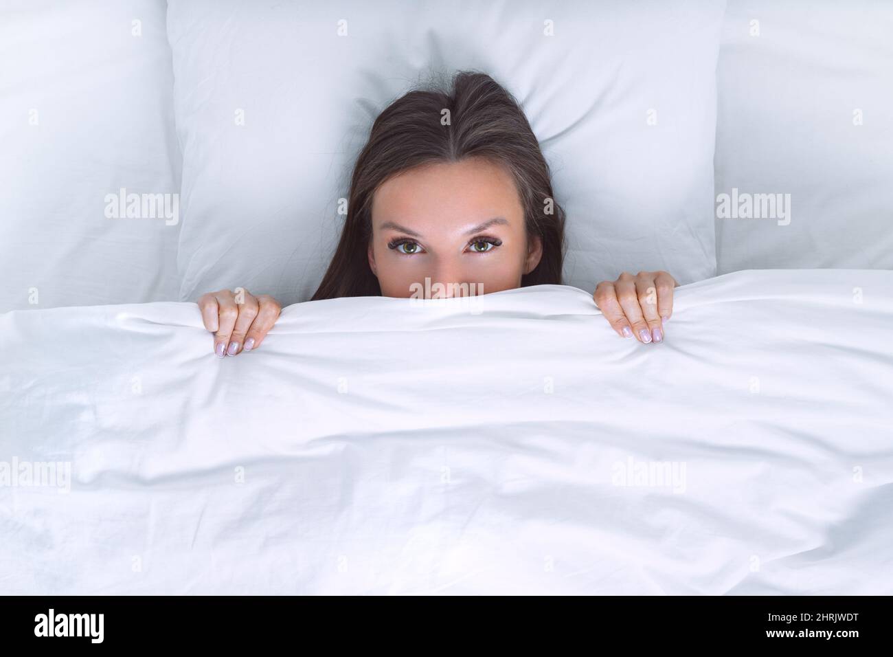 Attractive woman lying on the bed and covering half of face with ...