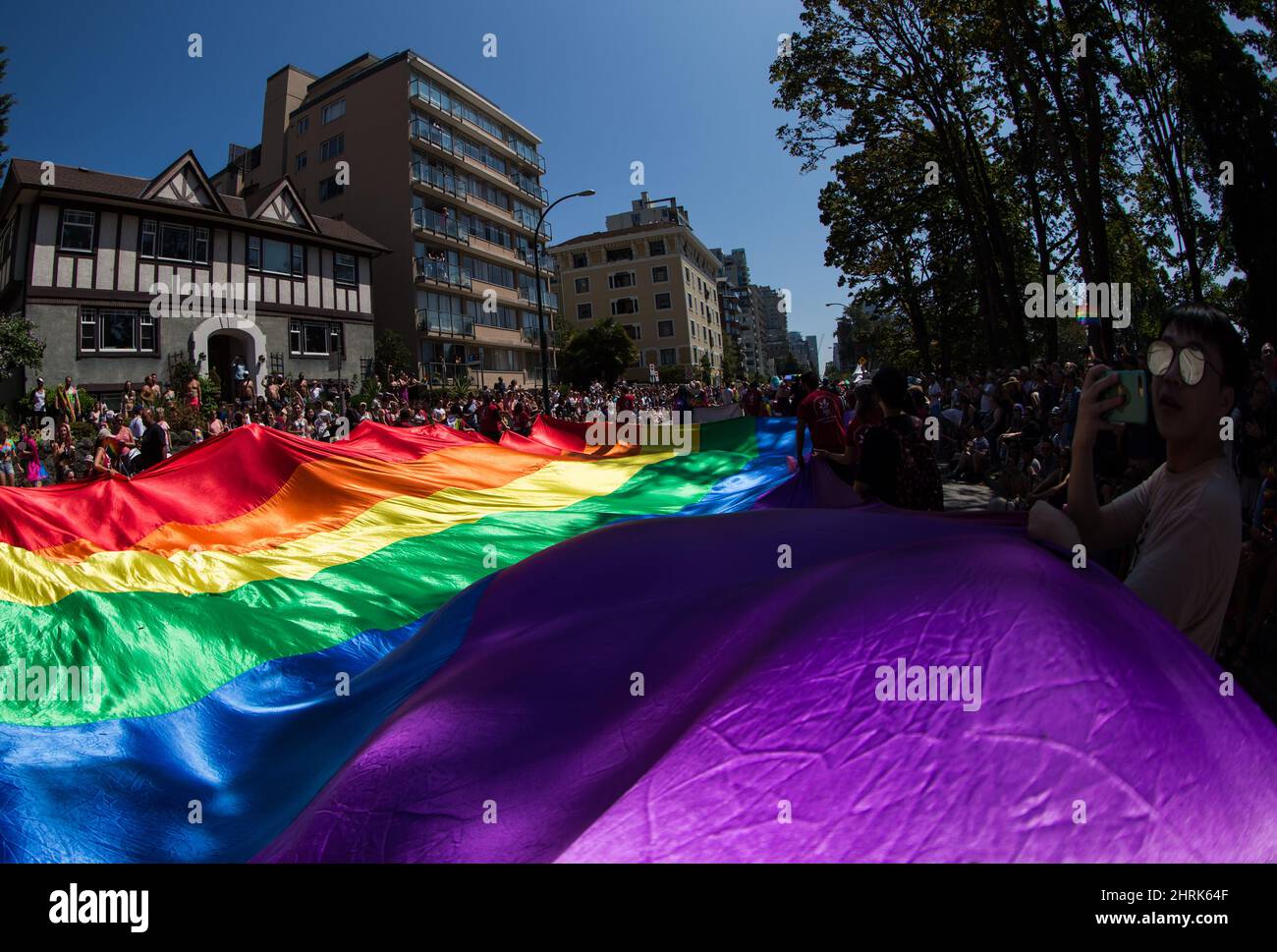A large rainbow flag is carried by people marching in the Vancouver ...