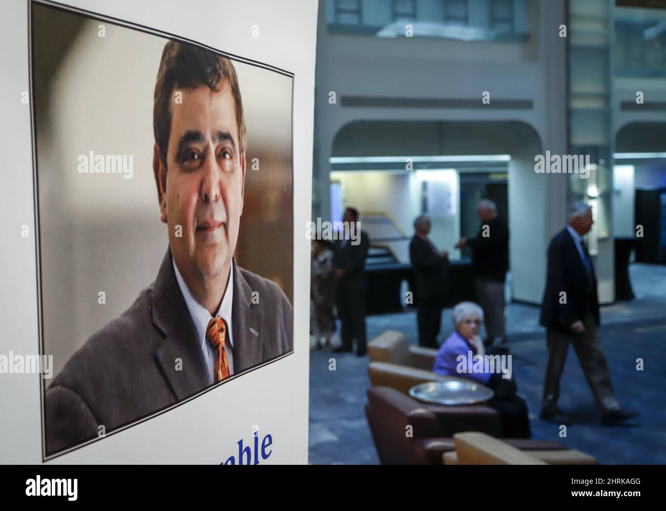 A photo of the late MP Deepak Obhrai looks lout over mourners at a ...