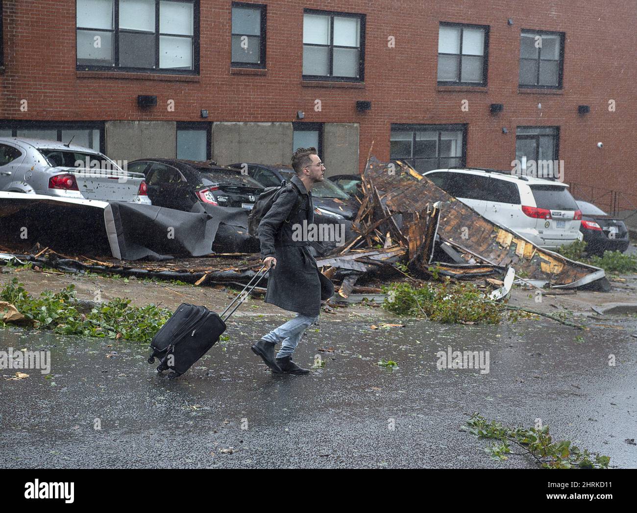 An unidentified man heads past part of an apartment roof that landed on ...