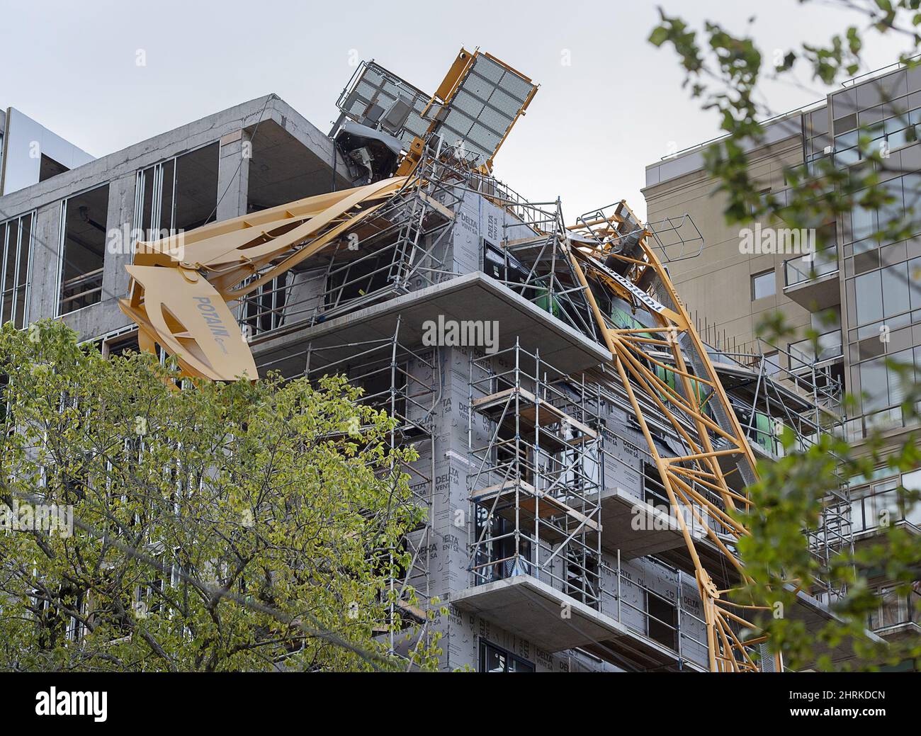 A toppled building crane is draped over a new construction project in ...