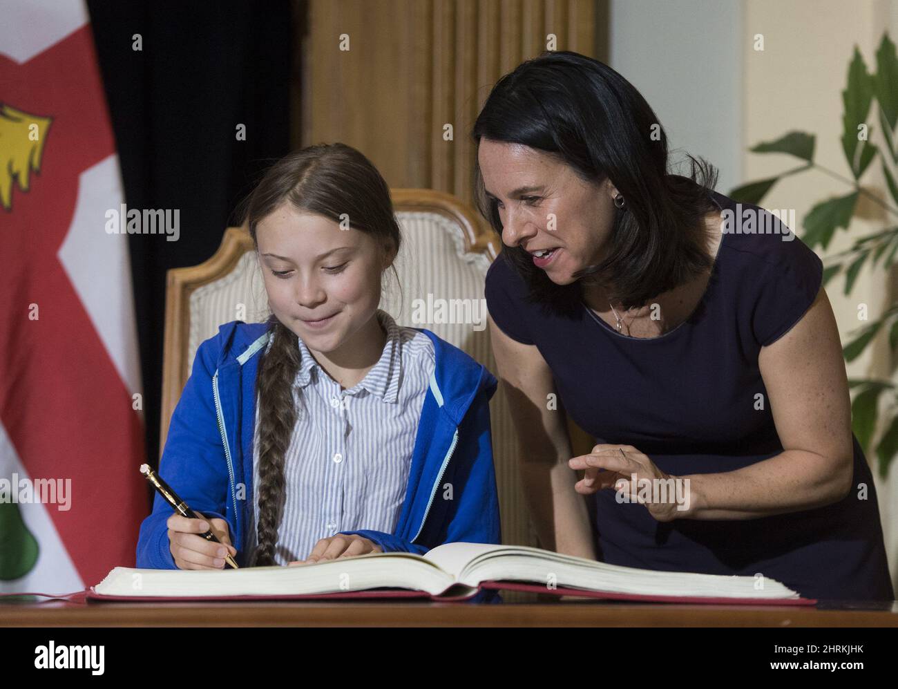 Swedish climate activist Greta Thunberg, left, signs the Golden Book ...