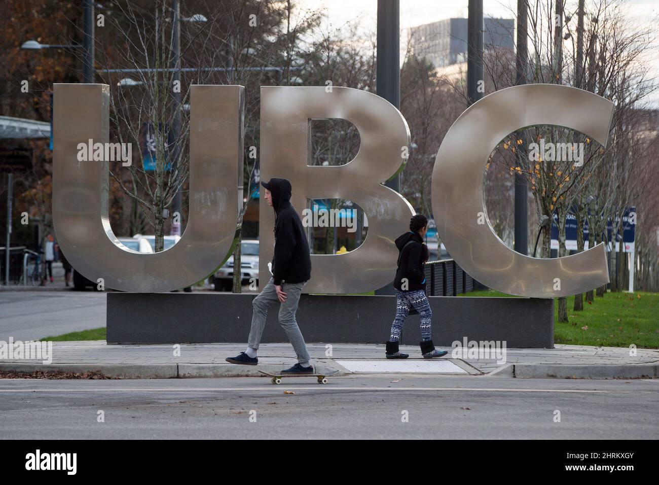 A man on a skateboard and a young woman pass large letters spelling out ...