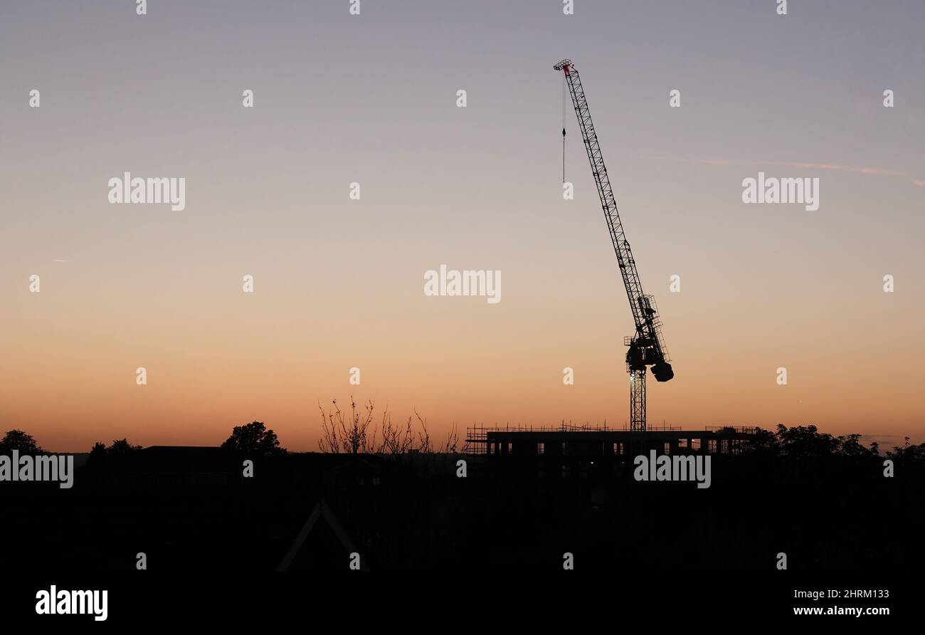 Crane towering over a construction site at dusk Stock Photo - Alamy