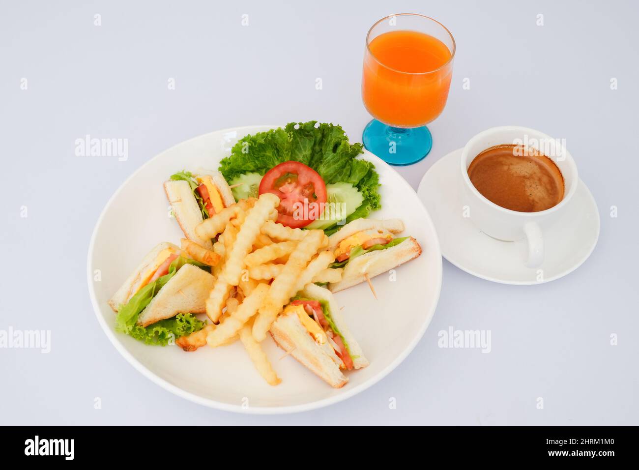 Serving of Club sandwich with French fries, vegetables, juice, and ...