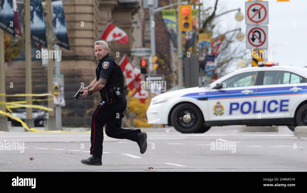 An Ottawa police officer runs with his weapon drawn in Ottawa on ...