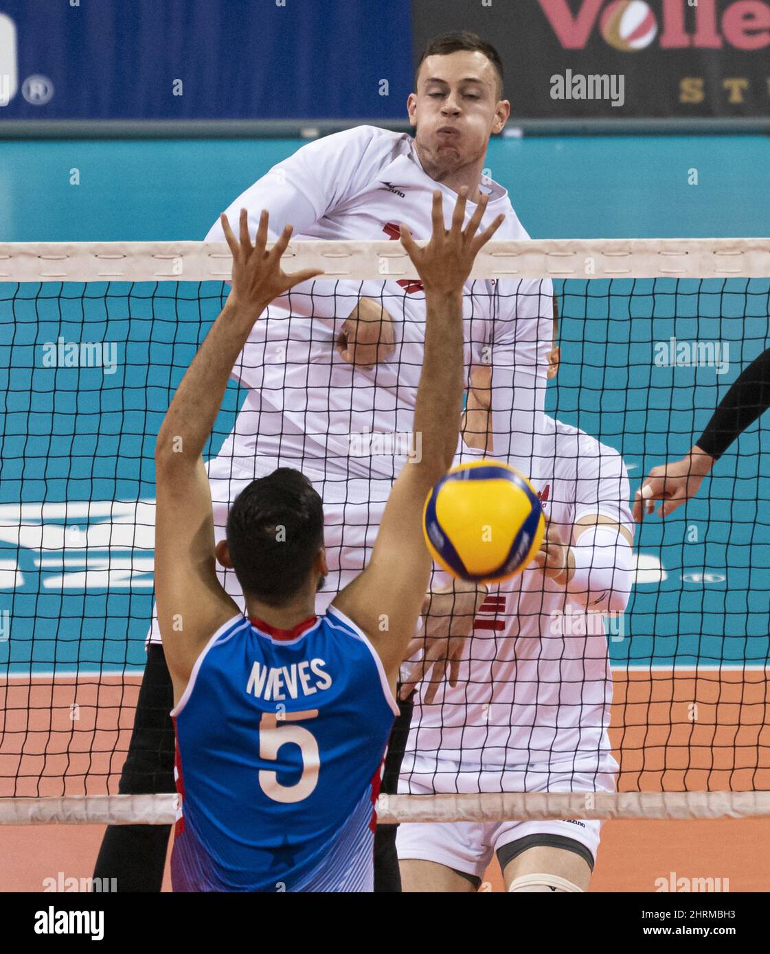 Graham Vigrass, of Canada, spikes the ball past the block of Pedro ...