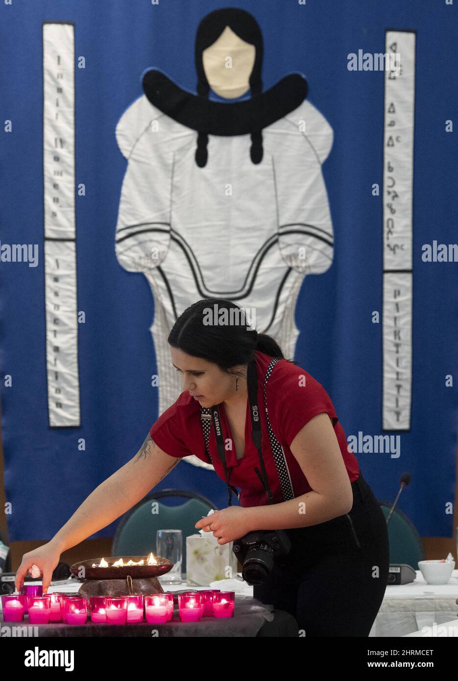 A woman lights candles next to the qulliq before the start of an Inuit ...