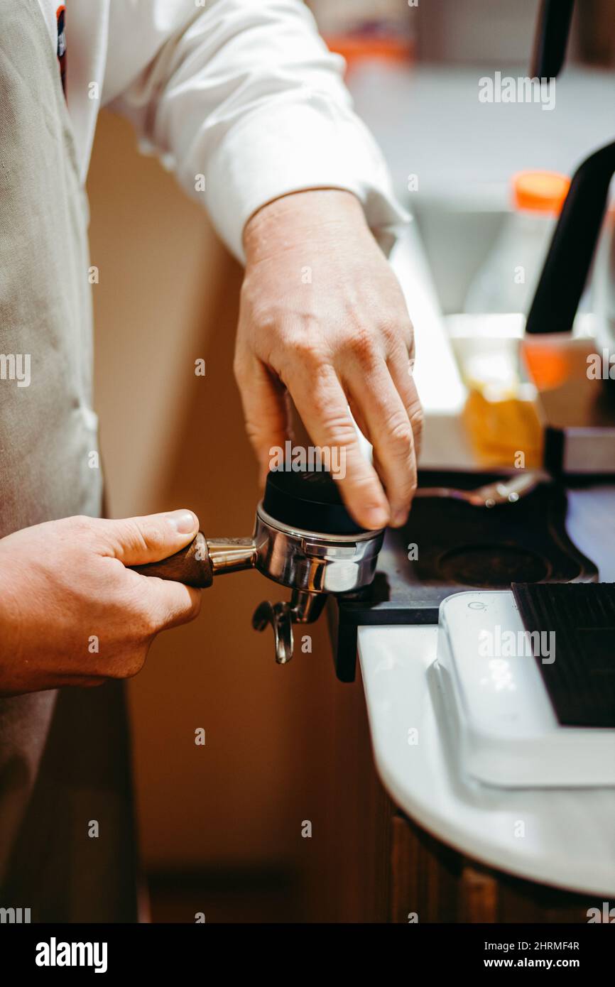 Shallow focus of a male hand preparing a cup for grounded coffee with a ...