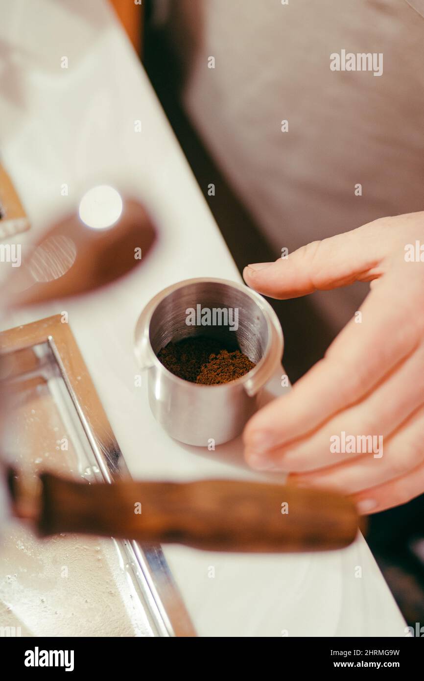 Shallow focus of a male hand preparing a cup for grounded coffee with a ...