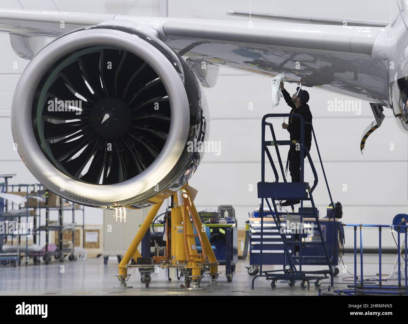 An Airbus employee works under the wing of an Airbus A220 at the ...