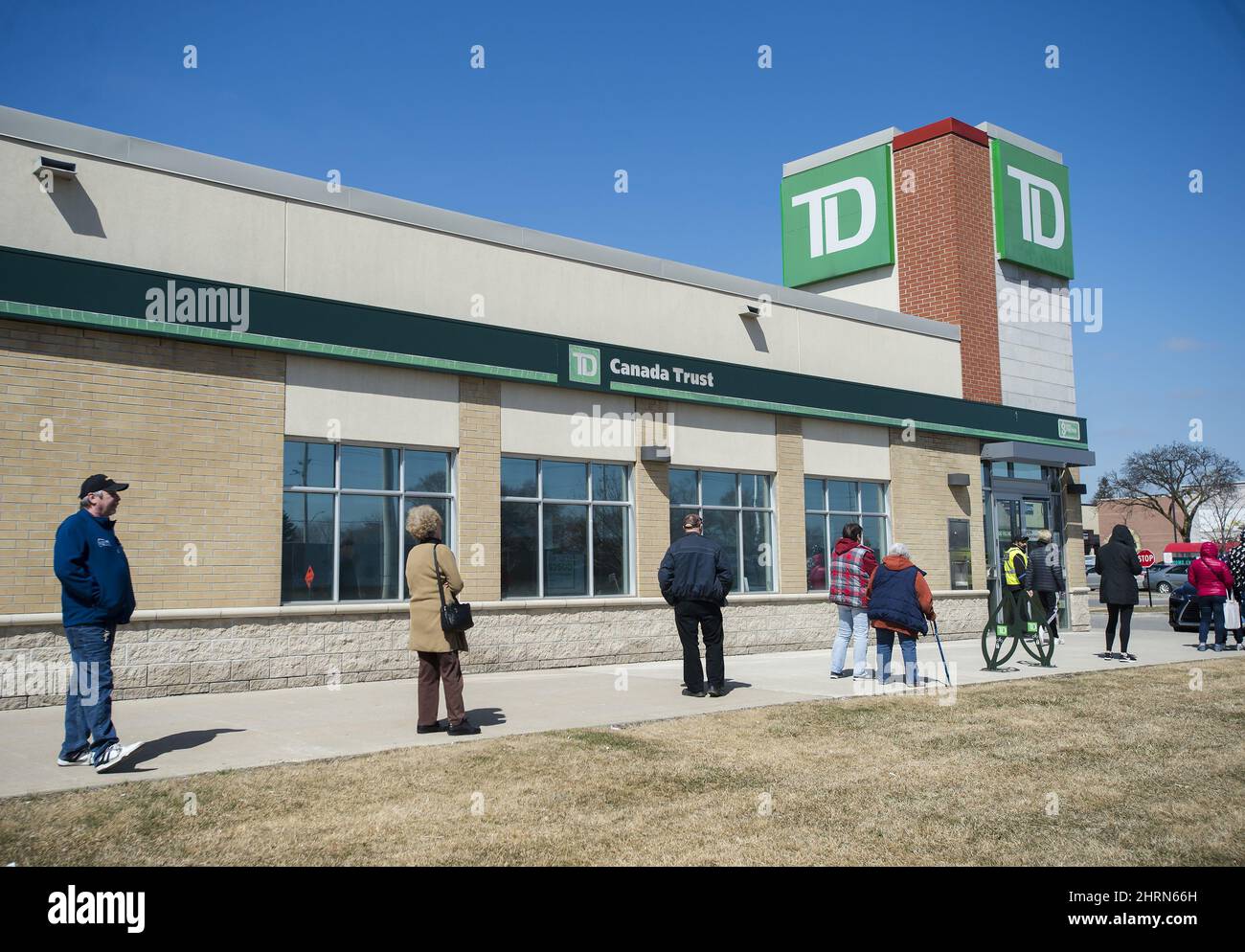 People line up outside of a TD Canada Trust bank while practising ...