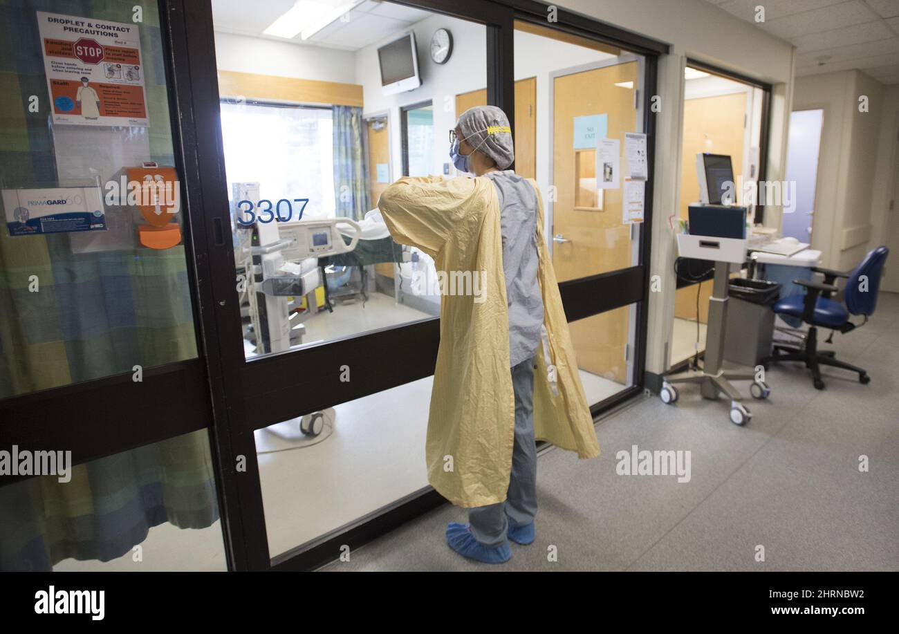 A nurse puts on her personal protective equipment prior to entering a ...