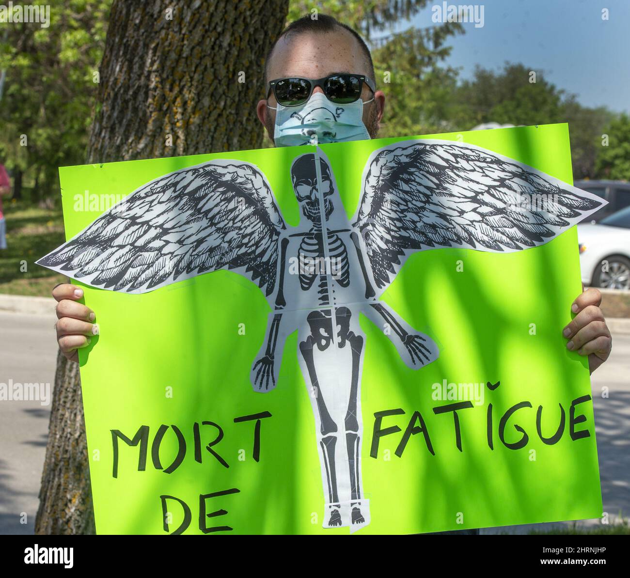 A healthcare worker holds a sign reading "death by fatigue" during a ...