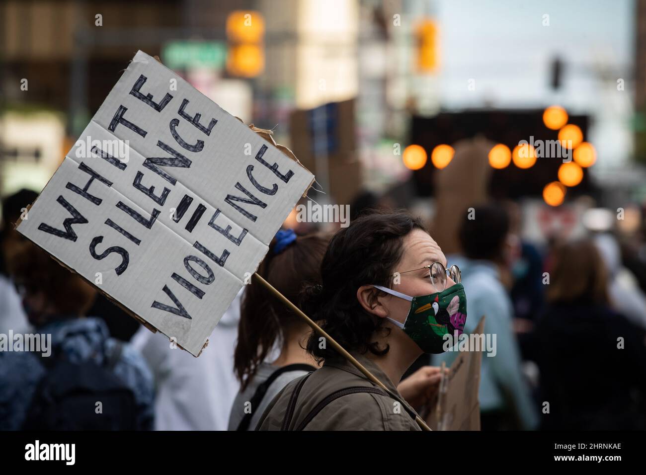 A woman holds a sign reading "White Silence = Violence" as thousands of ...