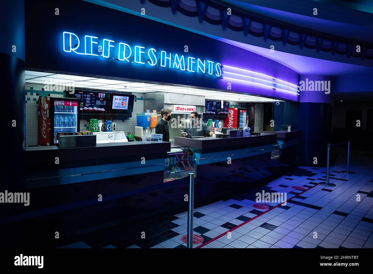 Wearing protective face masks and working behind plexiglass barriers at the concession stand ...