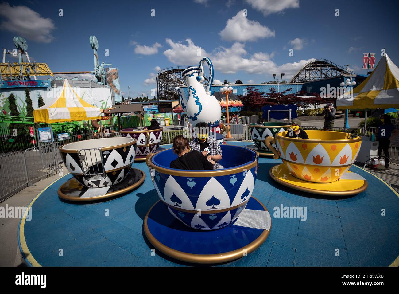 People wearing face masks ride the teacups attraction at Playland ...