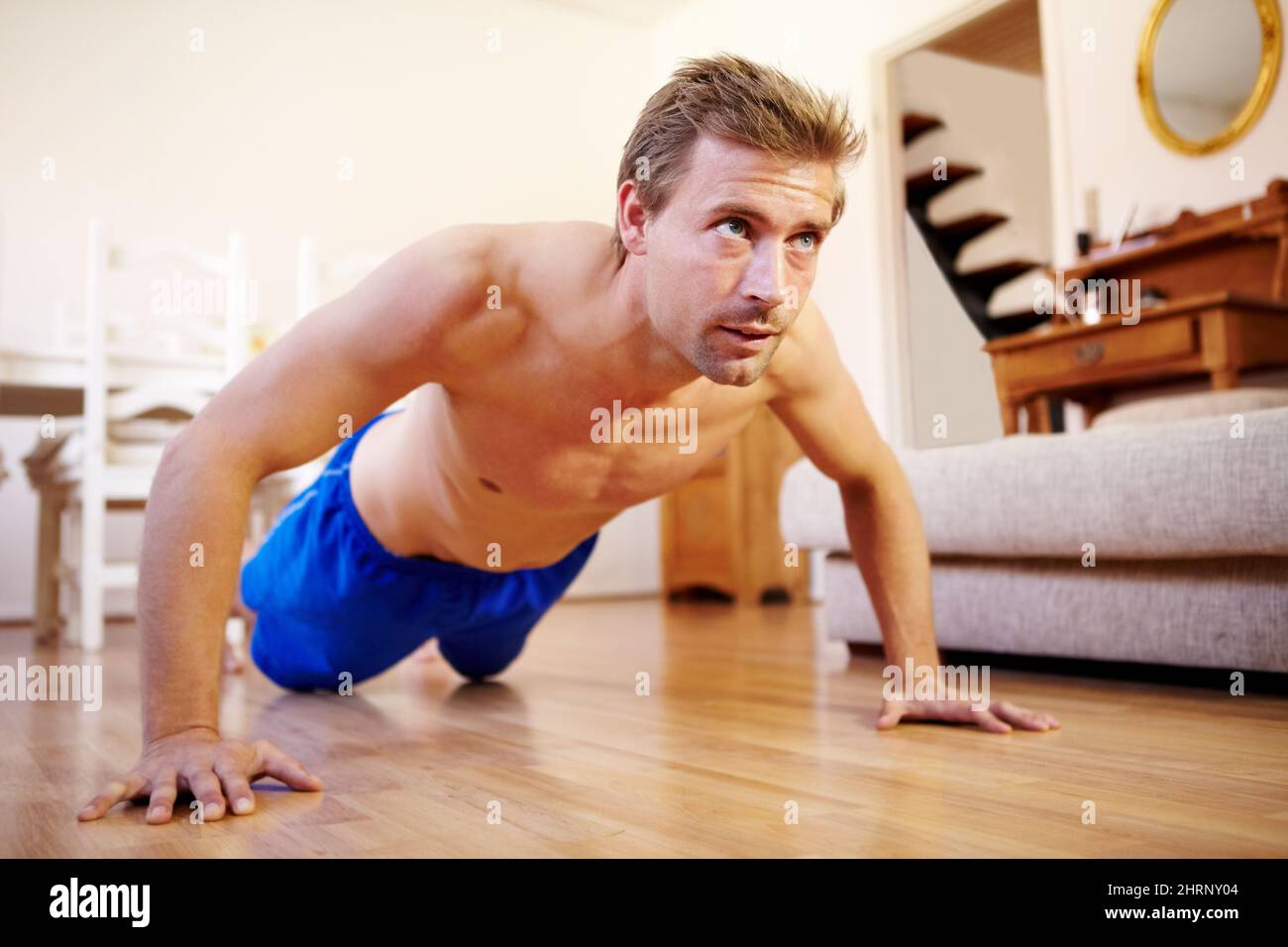 Determined to reach 100. Handsome young guy doing push-ups at home ...