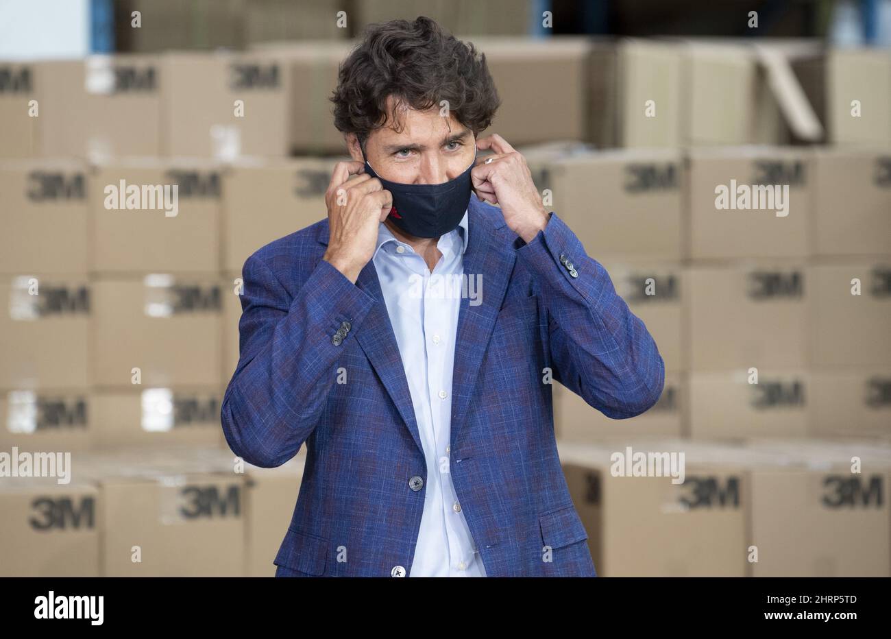 Prime Minister Justin Trudeau removes a cloth mask as he approaches the ...