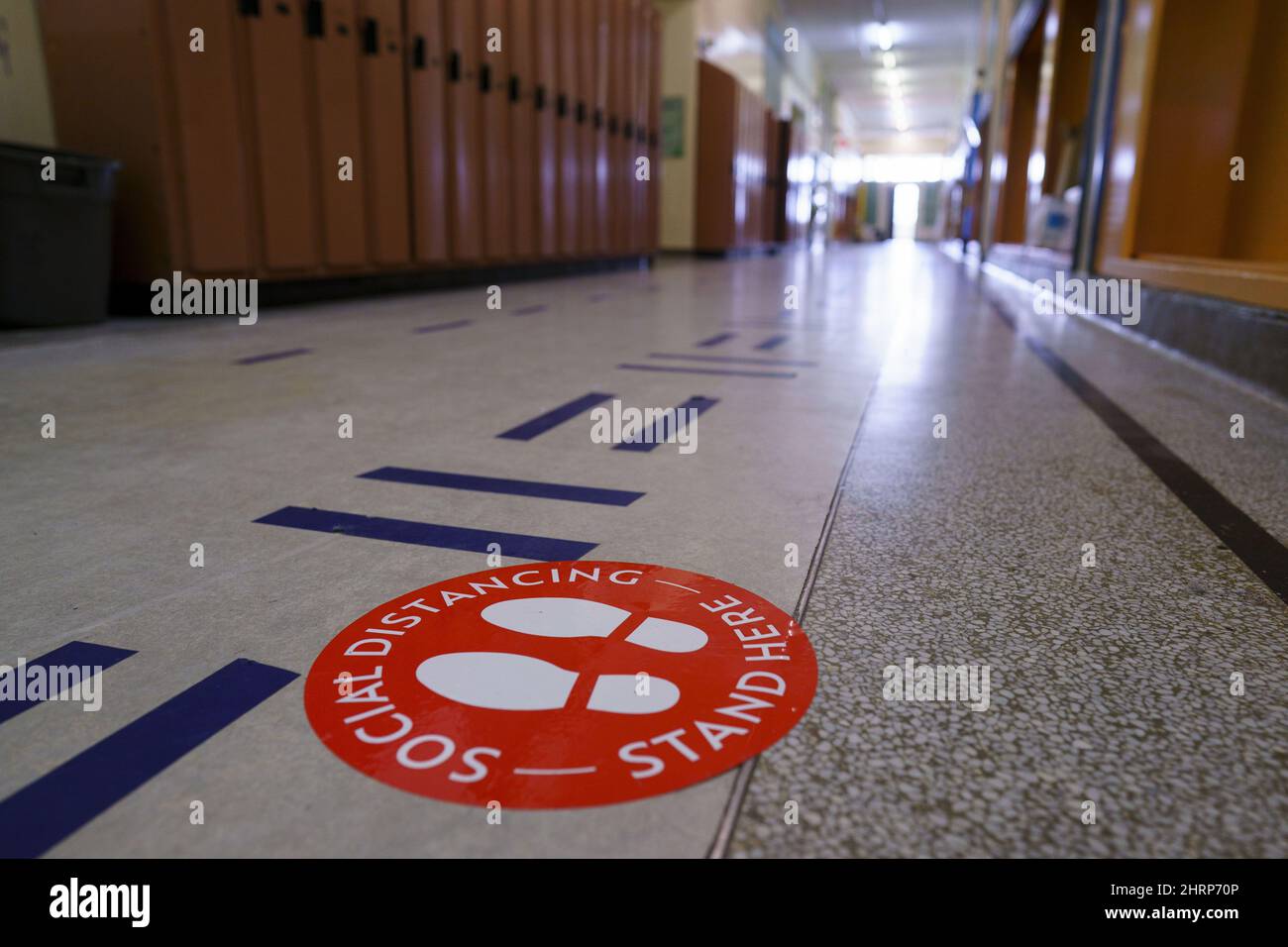A social distancing sticker is seen on the floor of a hallway in ...