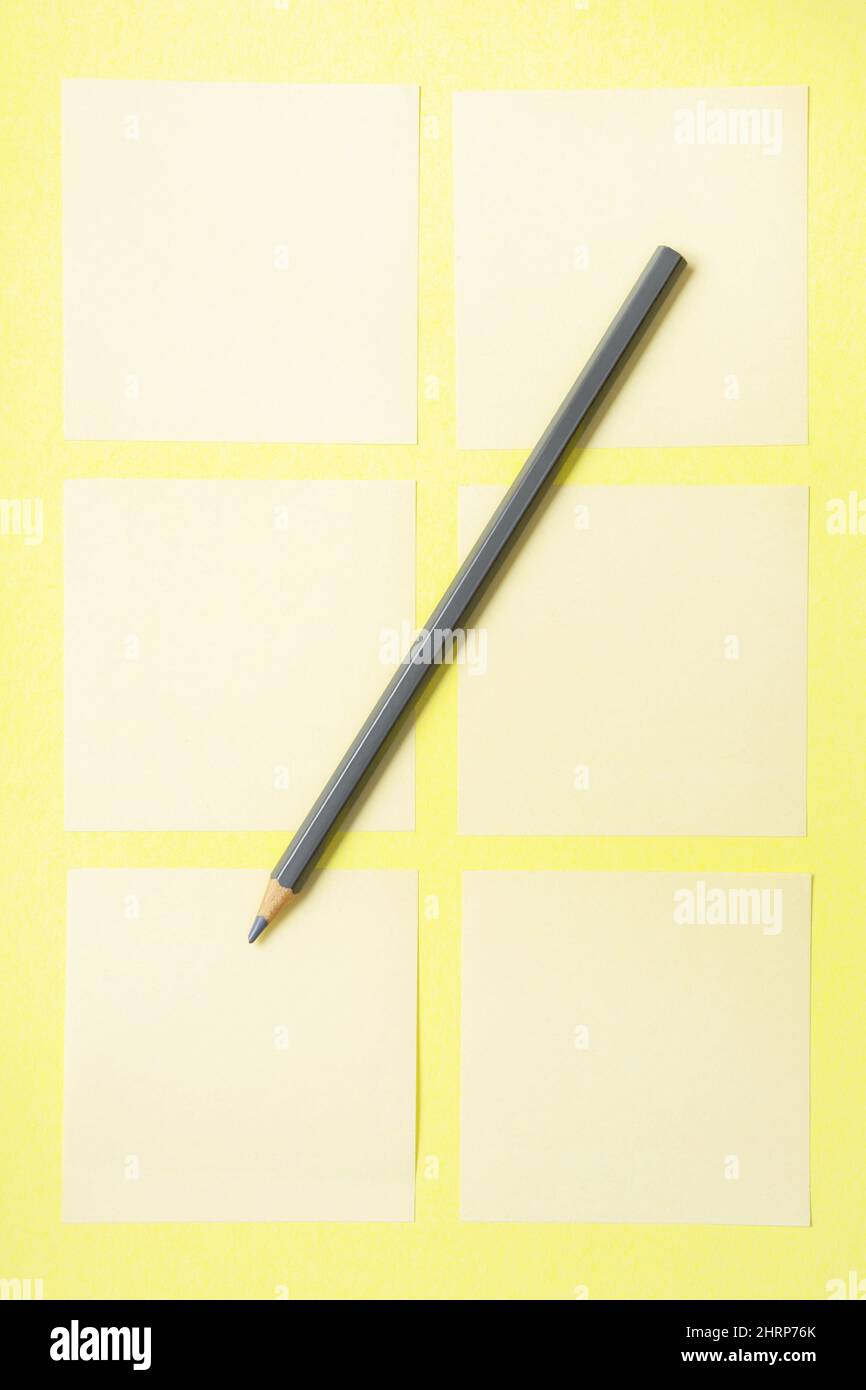 Top view of a gray pencil on yellow background with blank notes to ...