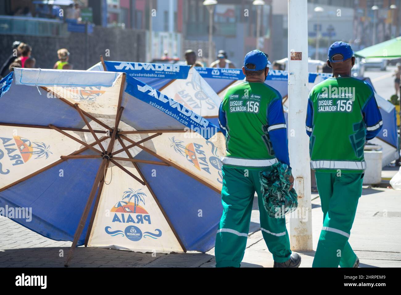 Rearview of two urban cleaning workers on the beach in Salvador, Bahia ...