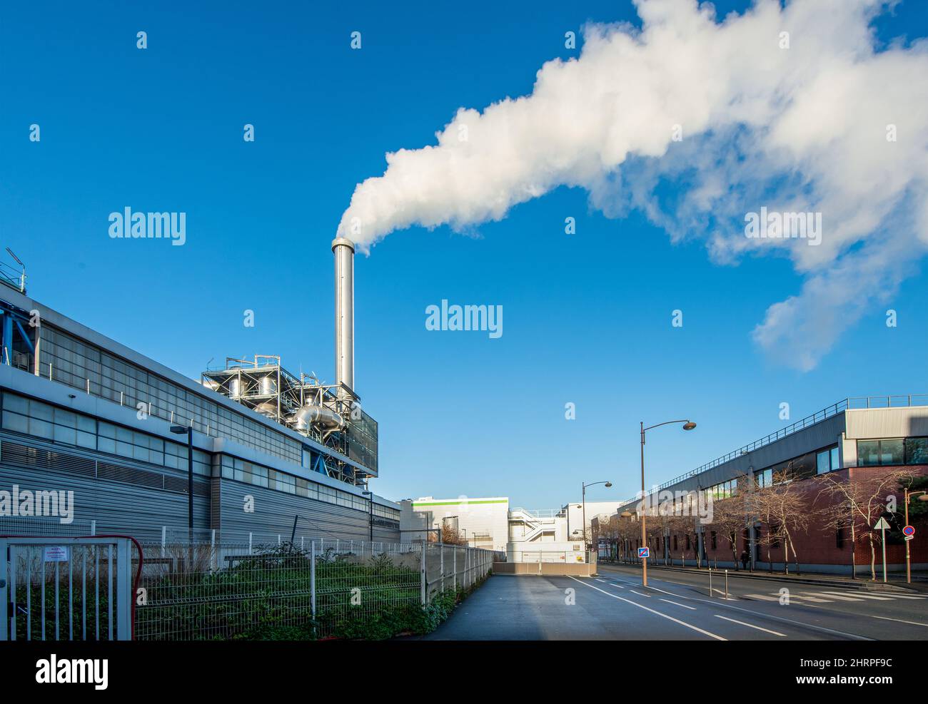 Waste treatment plant with smoking chimney in a busy industrial spot ...