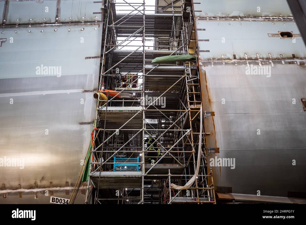 Workers climb scaffolding on a Joint Support Ship being built for the ...