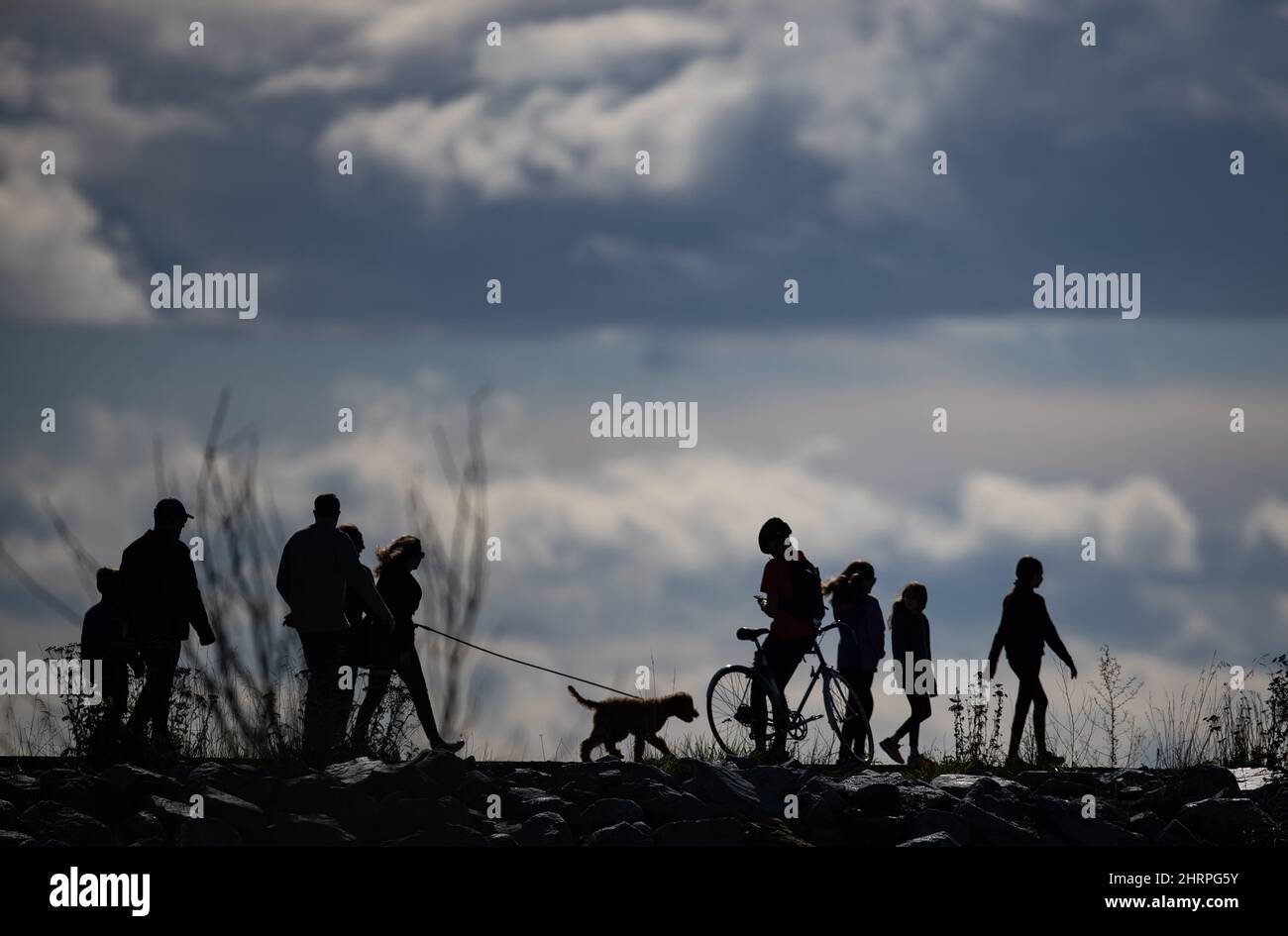 People are silhouetted while walking on the jetty at Iona Beach ...