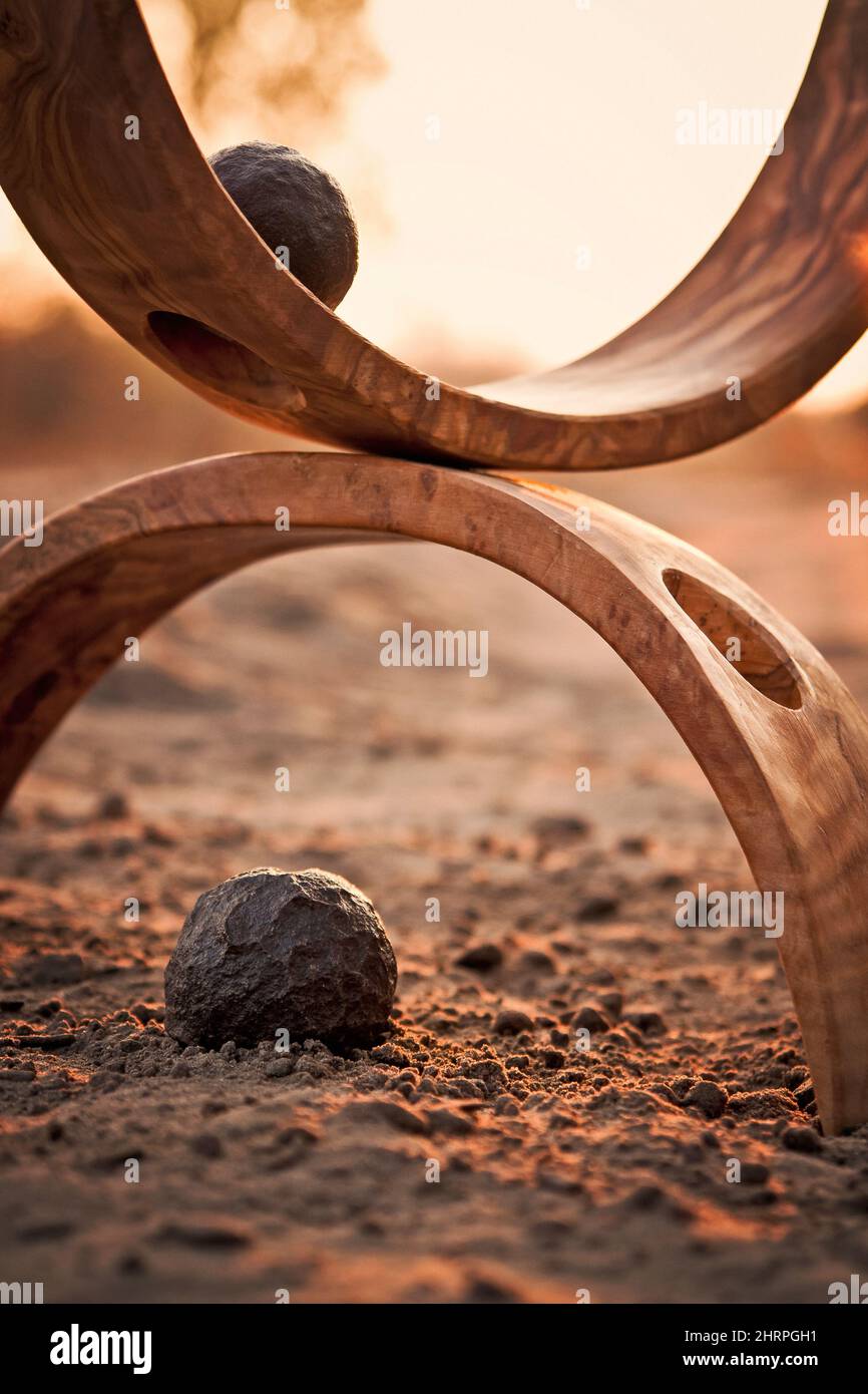 Vertical shot of rock balls under the half Moon shaped woods with a ...