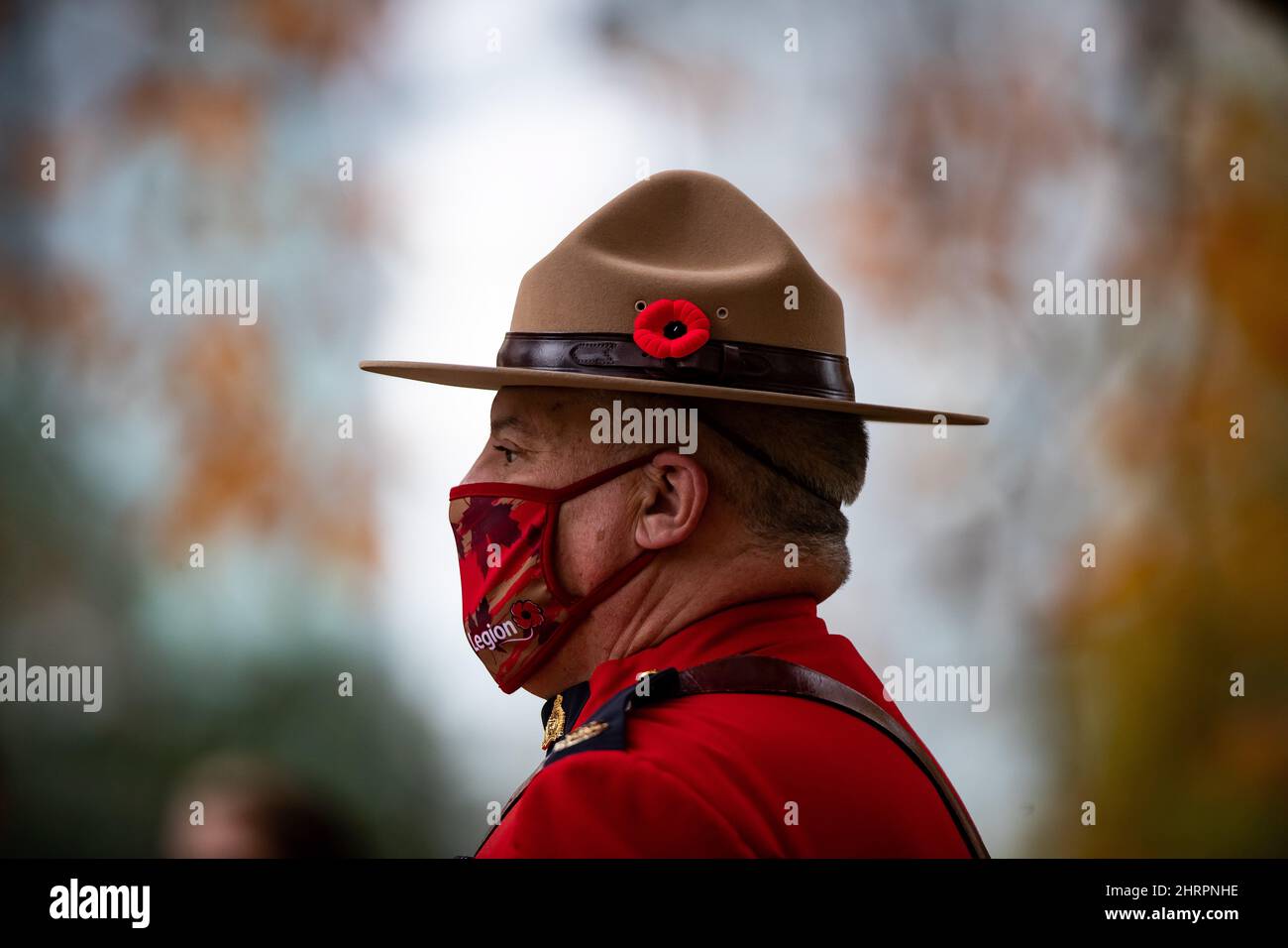 An RCMP officer in red serge sports a poppy on his stetson and wears a ...