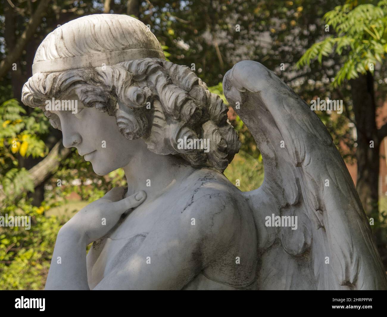Vertical shot of a female angel statue profile with the hand on a chest ...