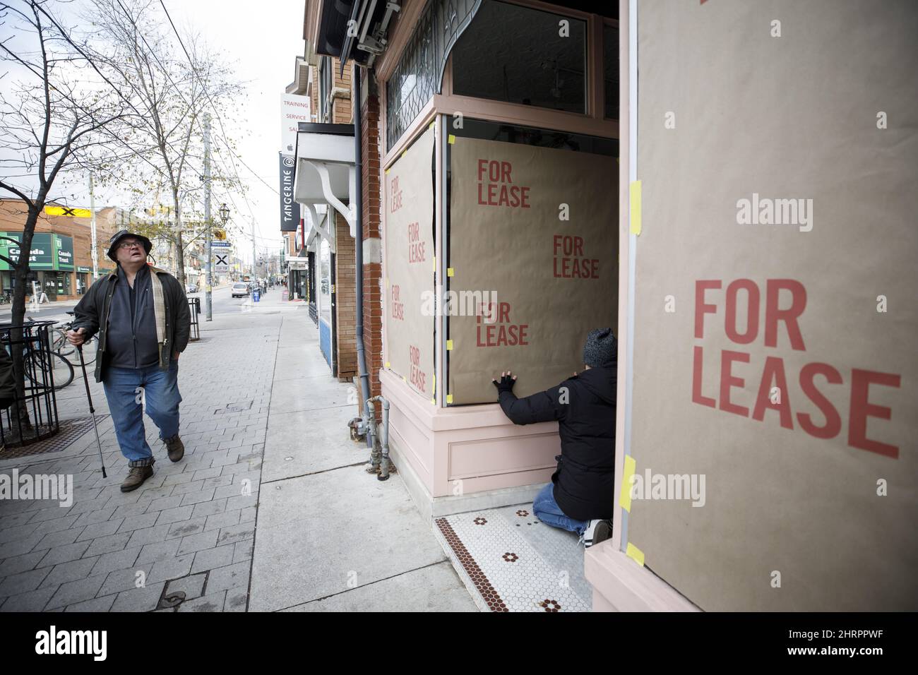 A worker posts fake 'For Lease' signage on storefronts in the ...