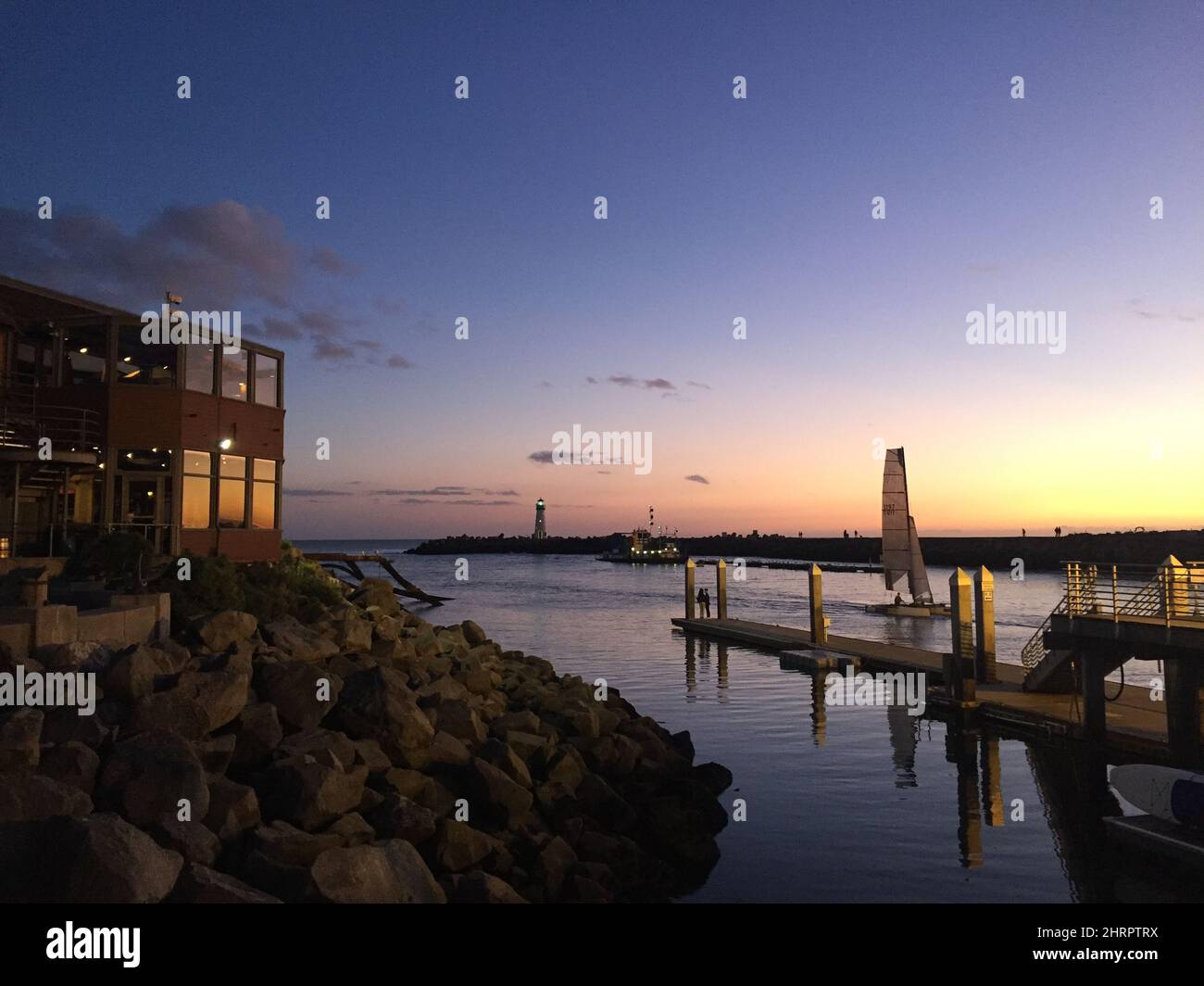 Scenic view of the dock with a lighthouse and water reflecting sunset ...