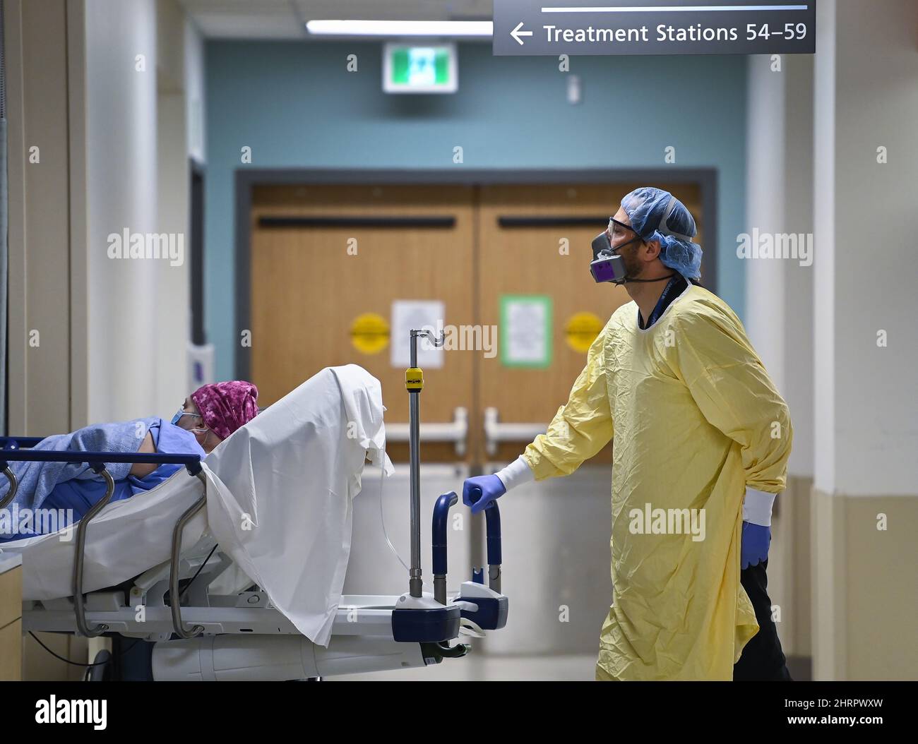 A health-care worker wearing PPE transports a patient in the dialysis ...