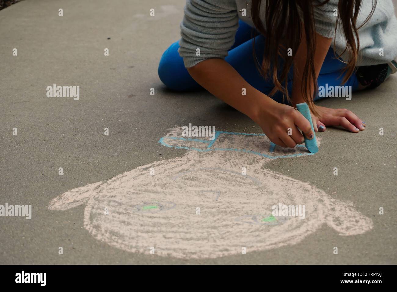 Young girl drawing a face with chalk on concrete pavement Stock Photo ...