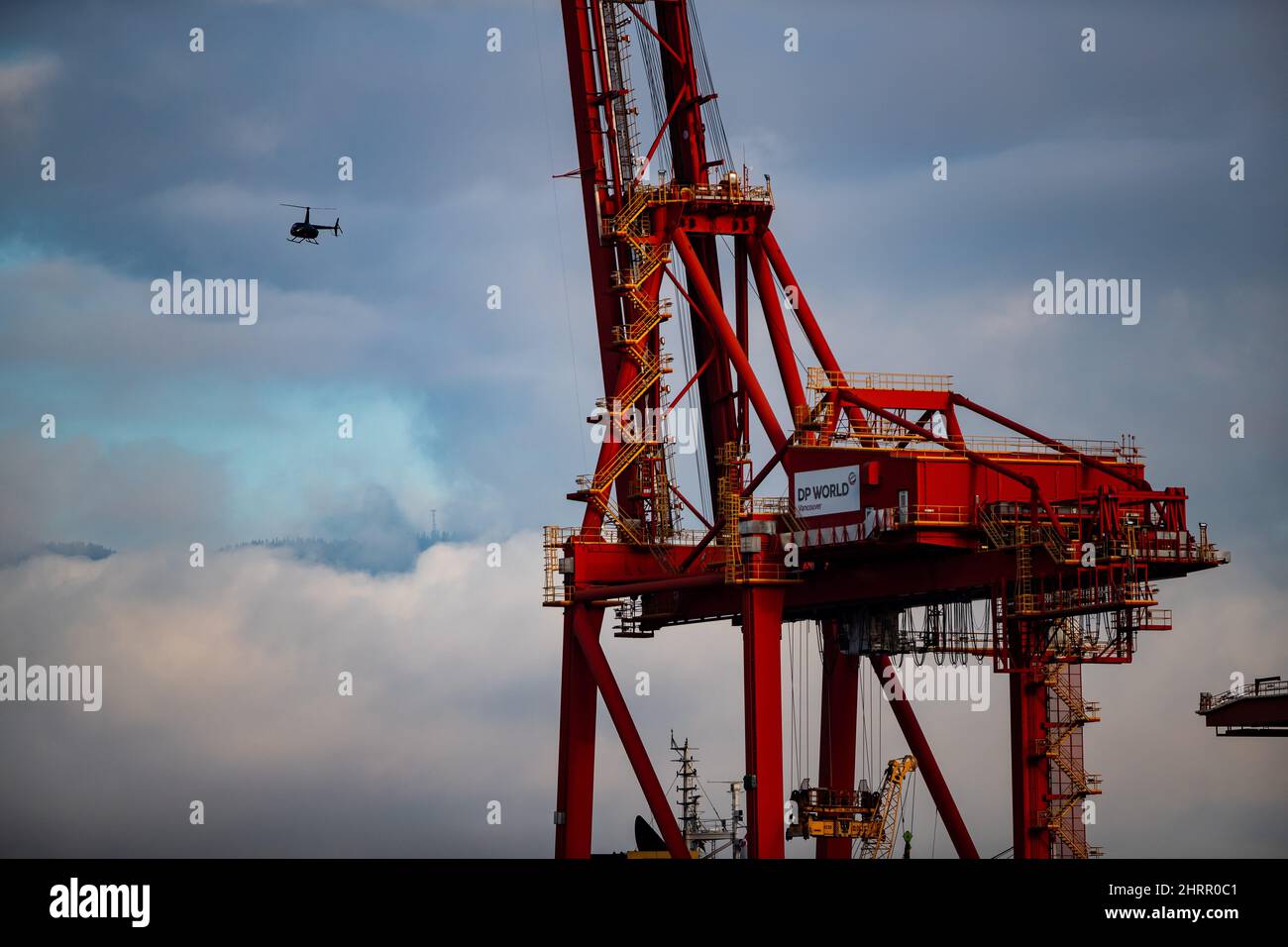 A helicopter preparing to land at a helipad on the harbour passes a ...
