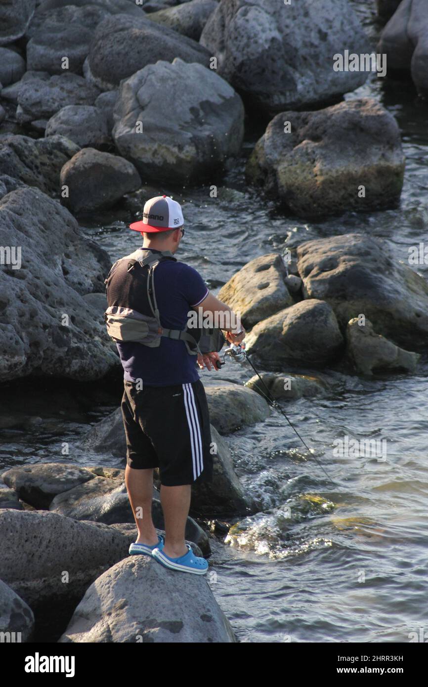 A fisherman balances on a rock as he fishes from the Sea of Galilee in ...