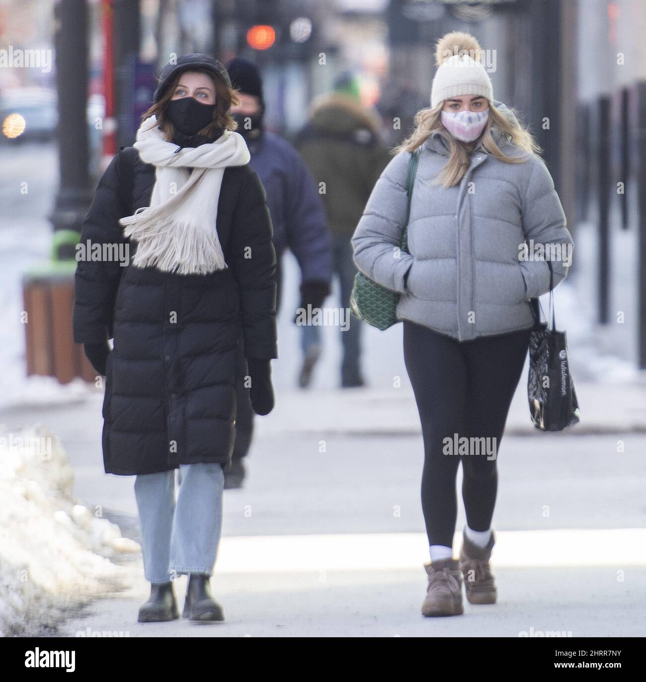 People wear face masks as they walk along a street in Montreal ...