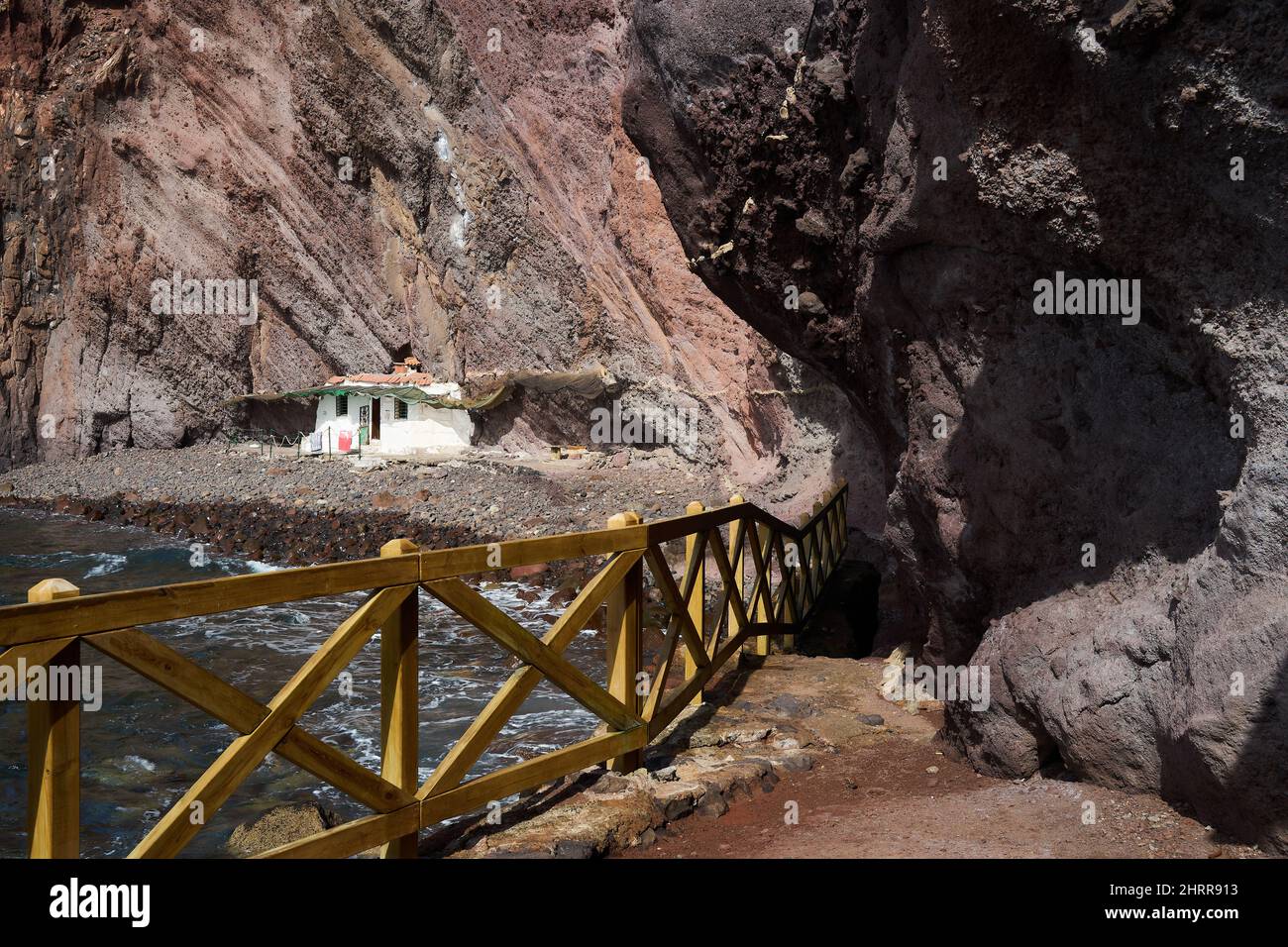 View of a house under rocks in Sardina de Galda beach Stock Photo - Alamy