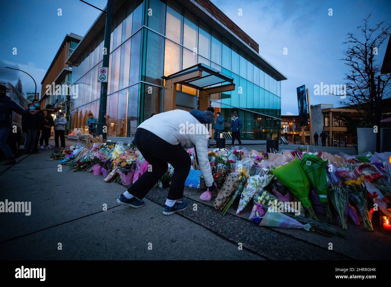 A person places flowers at a memorial outside the Lynn Valley Library ...