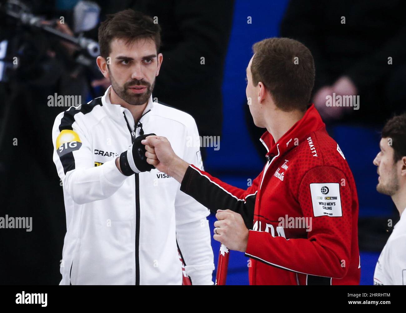 Switzerland skip Peter De Cruz, left, bumps fists with Team Canada skip ...
