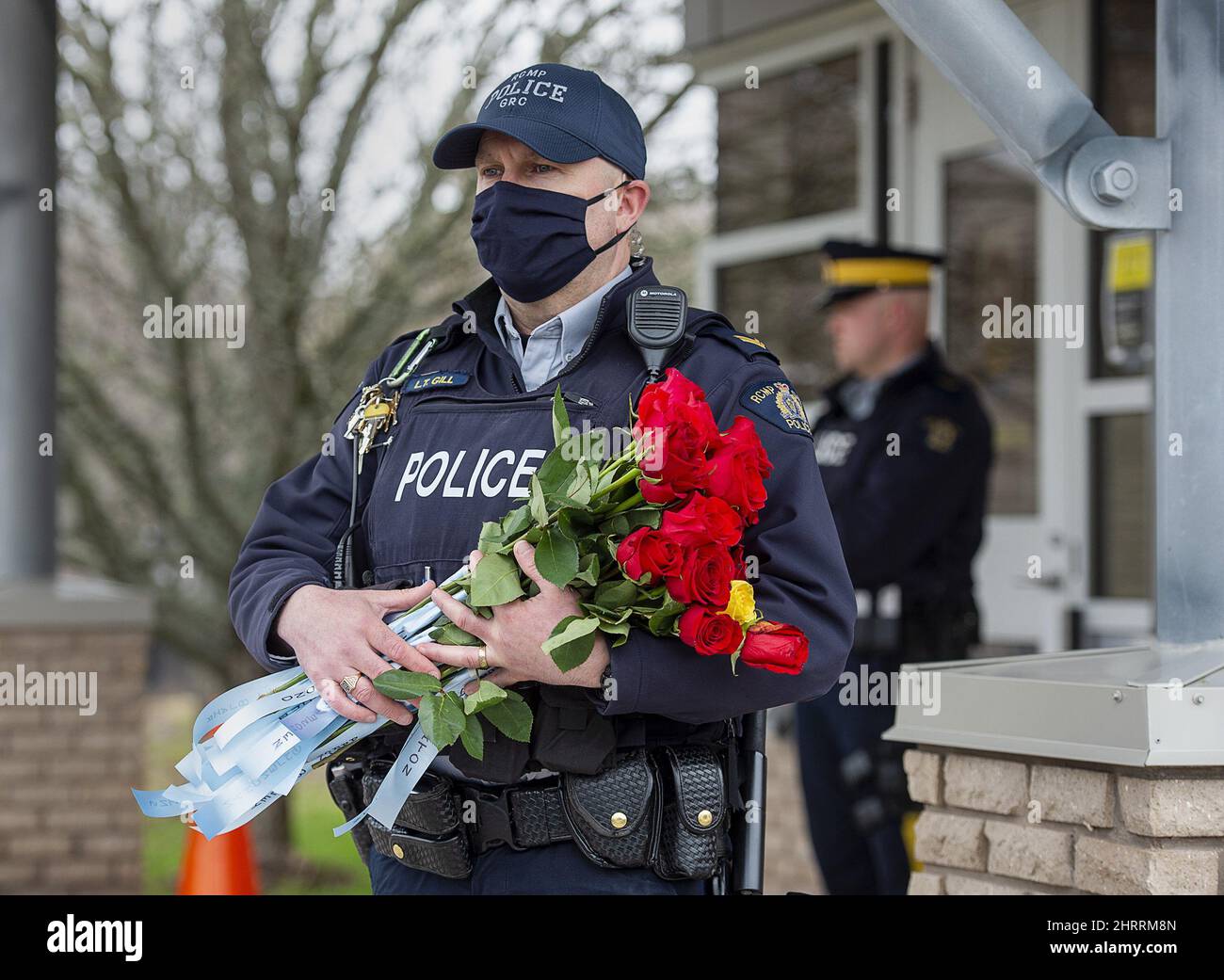 An RCMP officer holds roses, presented by family members of the victims ...