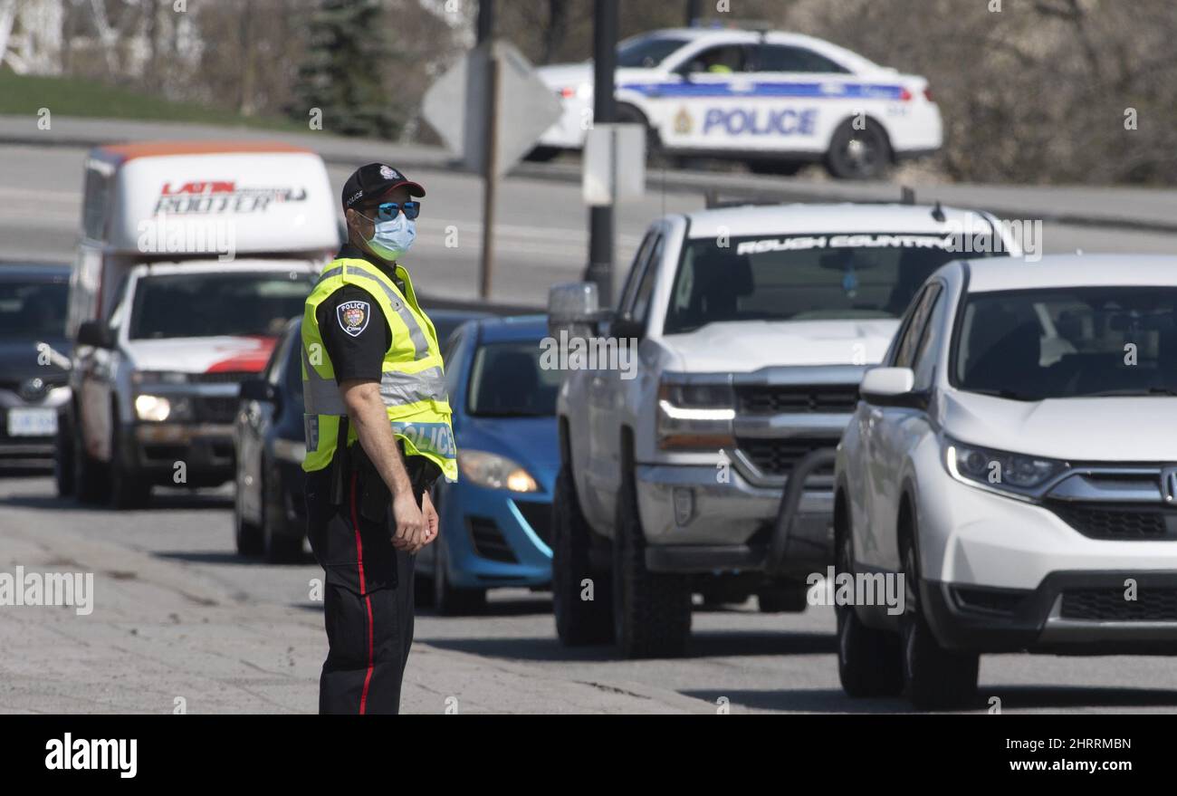 An Ottawa police officer watches as vehicles approach a checkpoint ...