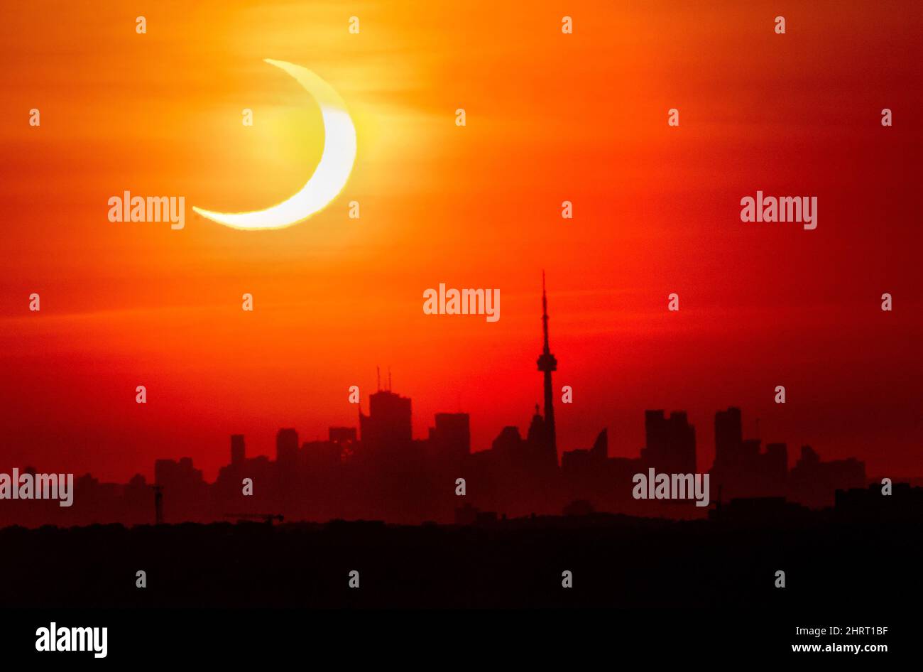 An annular solar eclipse rises over the skyline of Toronto on Thursday ...