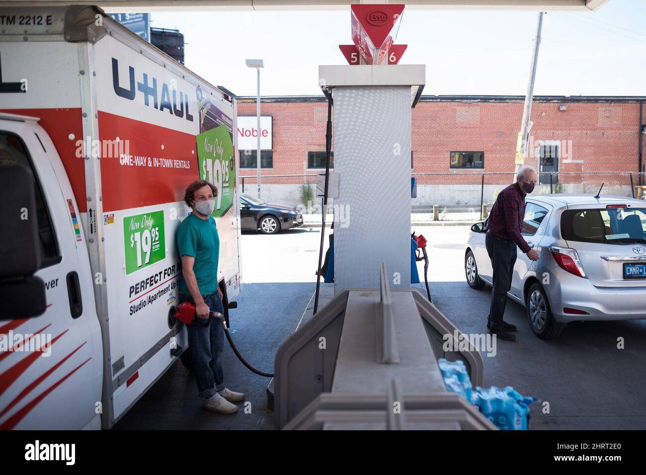 People pump gas into their vehicles at a Esso gas station in Toronto on ...